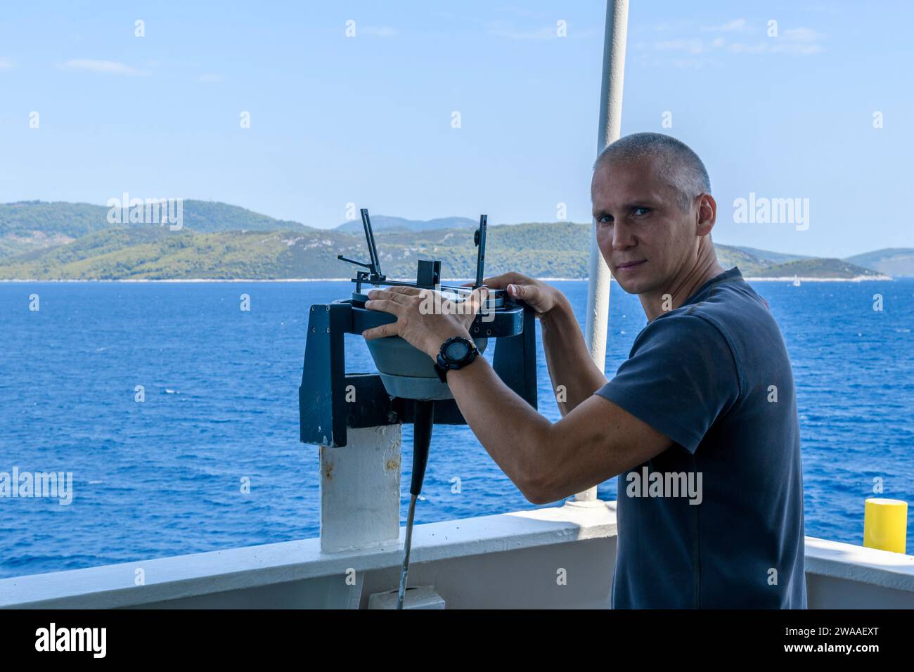 Navigational officer taking bearing with azimuth ring on gyro compass ...