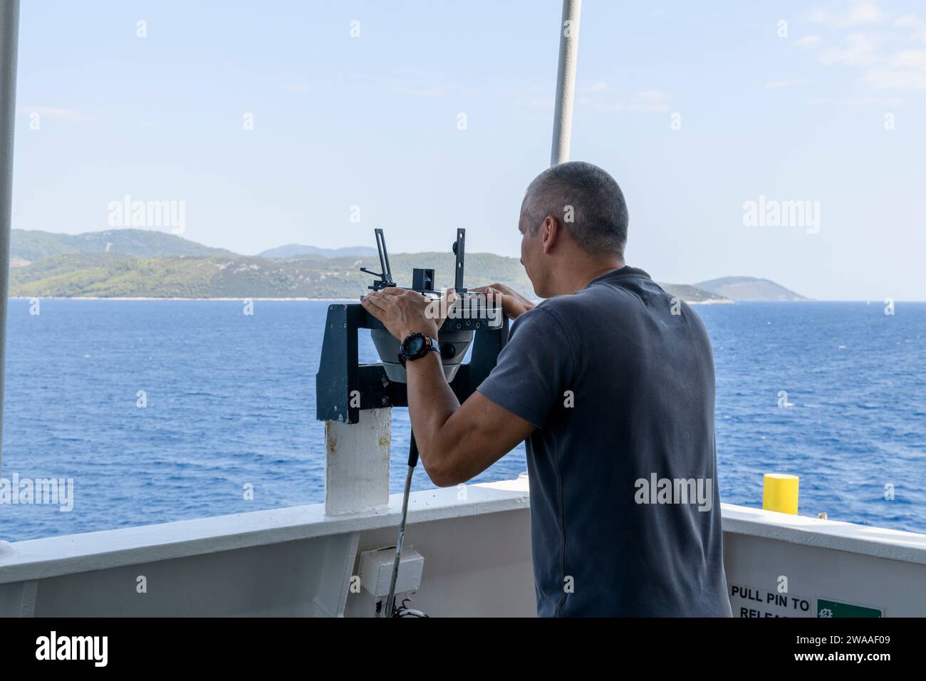 Navigational officer taking bearing with azimuth ring on gyro compass ...