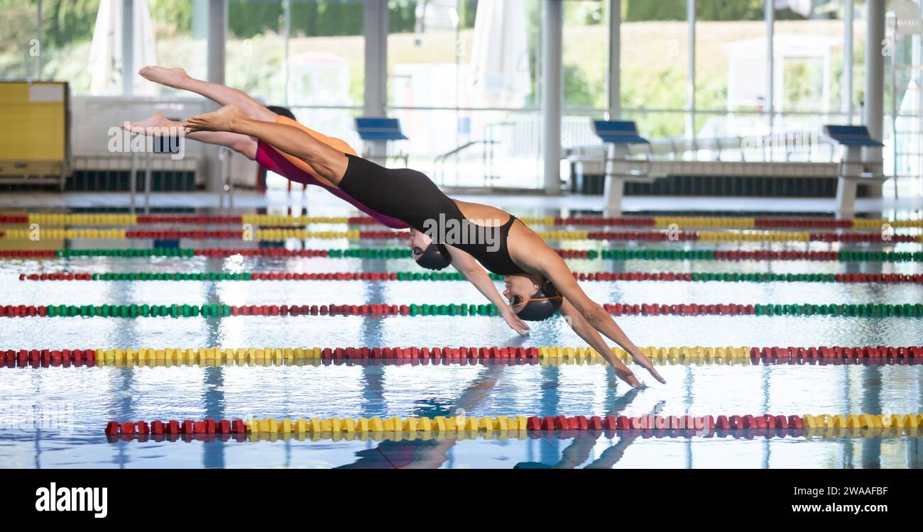 Professional female swimmer preparing and jumping off the starting ...