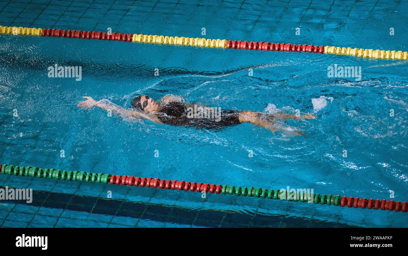 Female athlete in action, performing the backstroke swim technique in ...