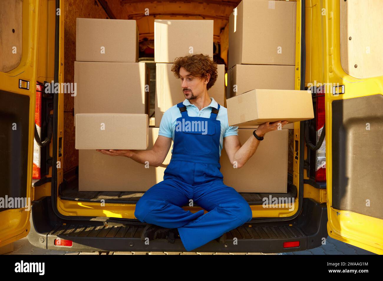 Delivery courier comparing parcel boxes Stock Photo - Alamy