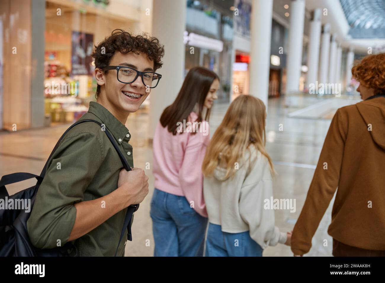 Portrait of happy teenage by turning his back while walking with ...
