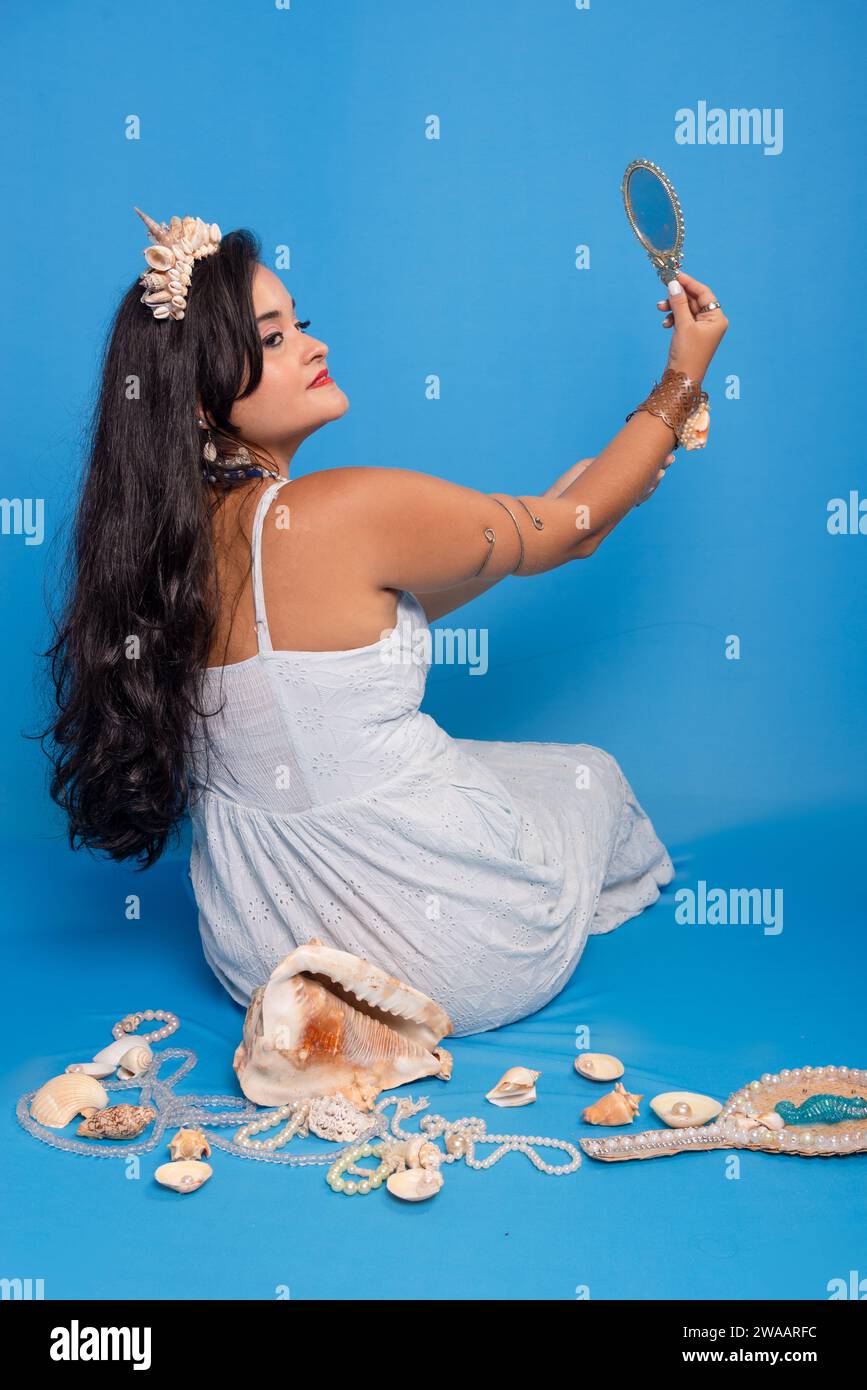 Beautiful black-haired woman wearing white clothing, sitting against ...
