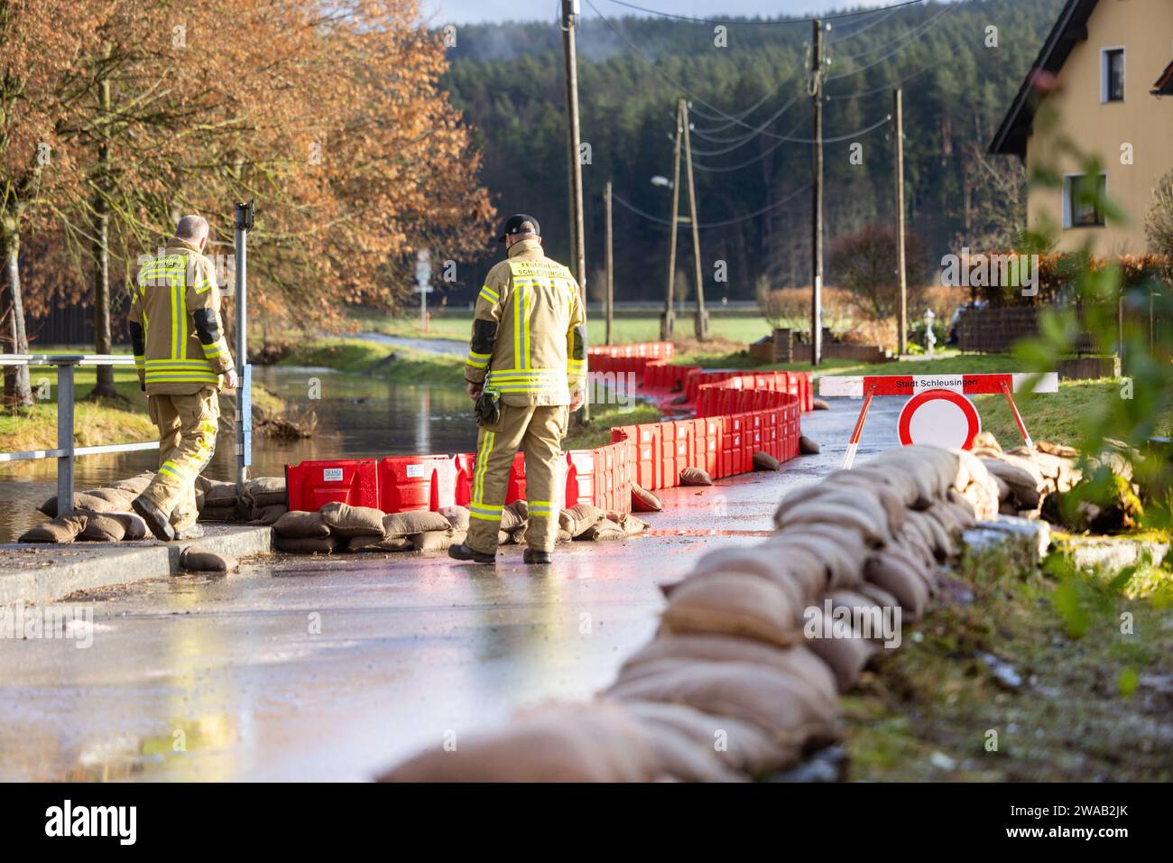 Schleusingen, Germany. 03rd Jan, 2024. Firefighters check a mobile dam ...