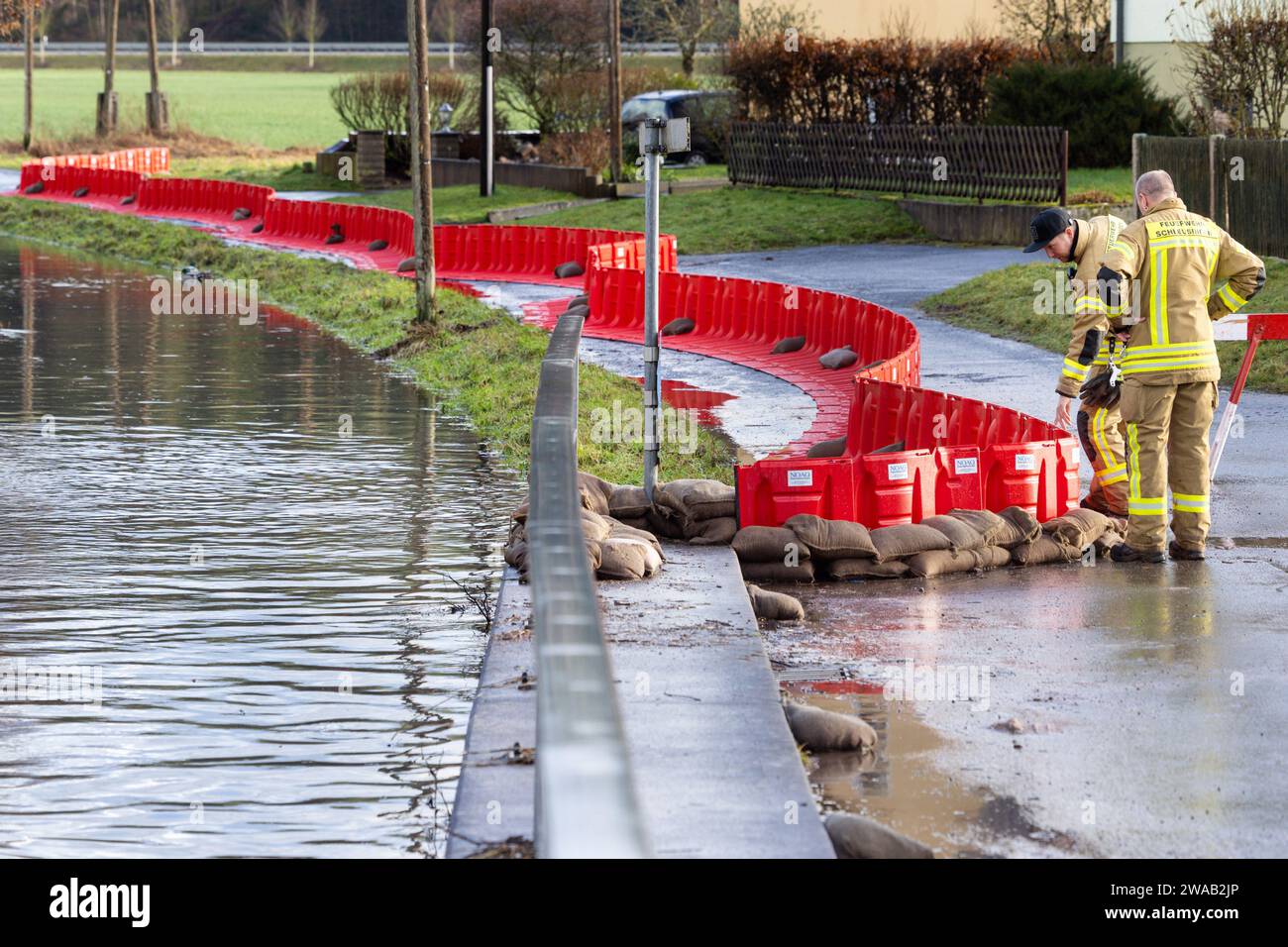 Schleusingen, Germany. 03rd Jan, 2024. Firefighters check a mobile dam ...