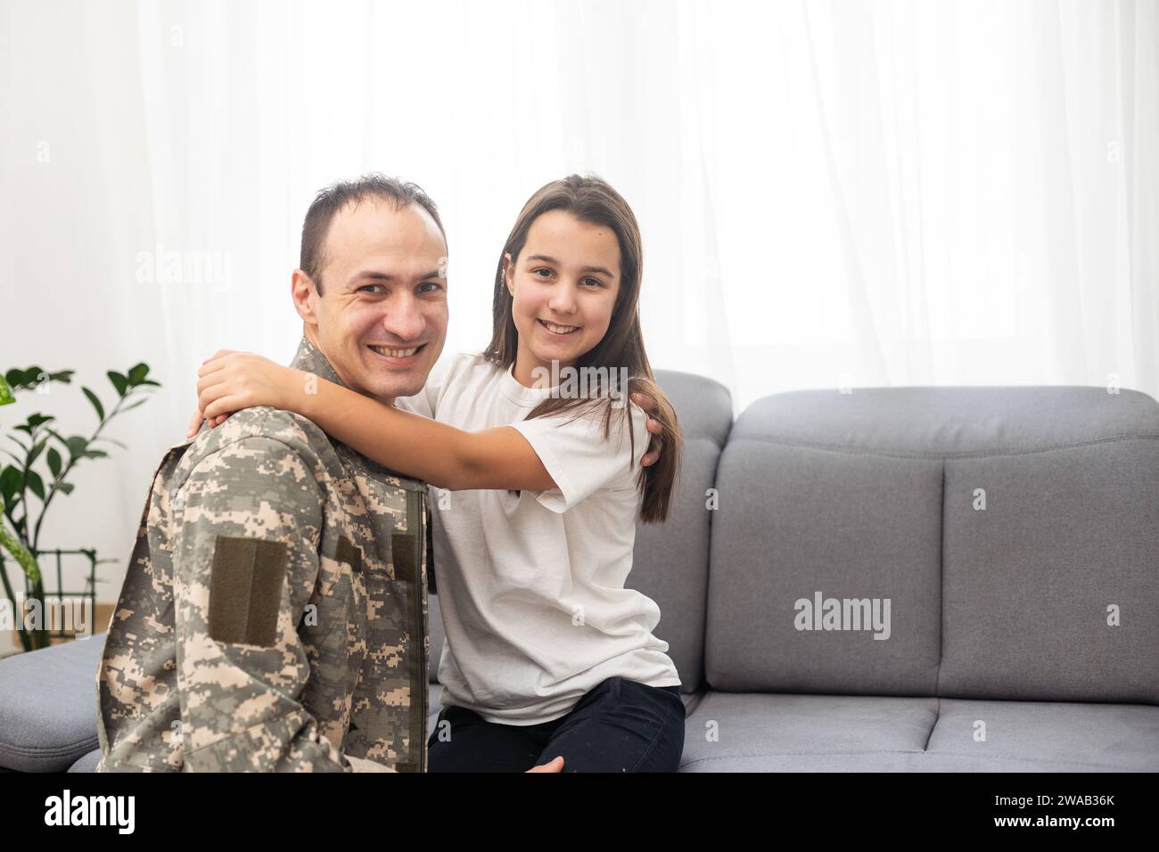 Young man in military uniform with his wife on sofa at home Stock Photo ...