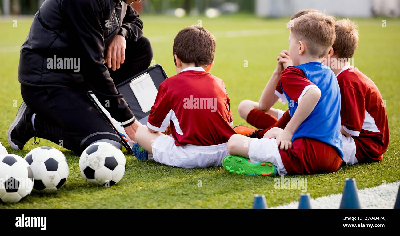 Soccer training for children. Kids and coach sitting on the football ...