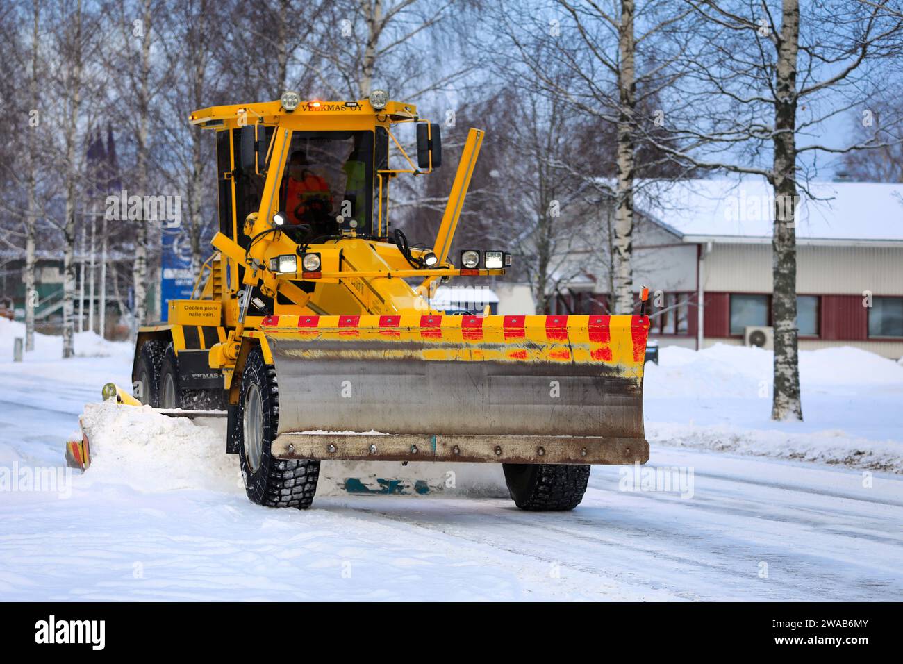 Yellow motor grader Veekmas FG 2327 S removing snow from street with ...