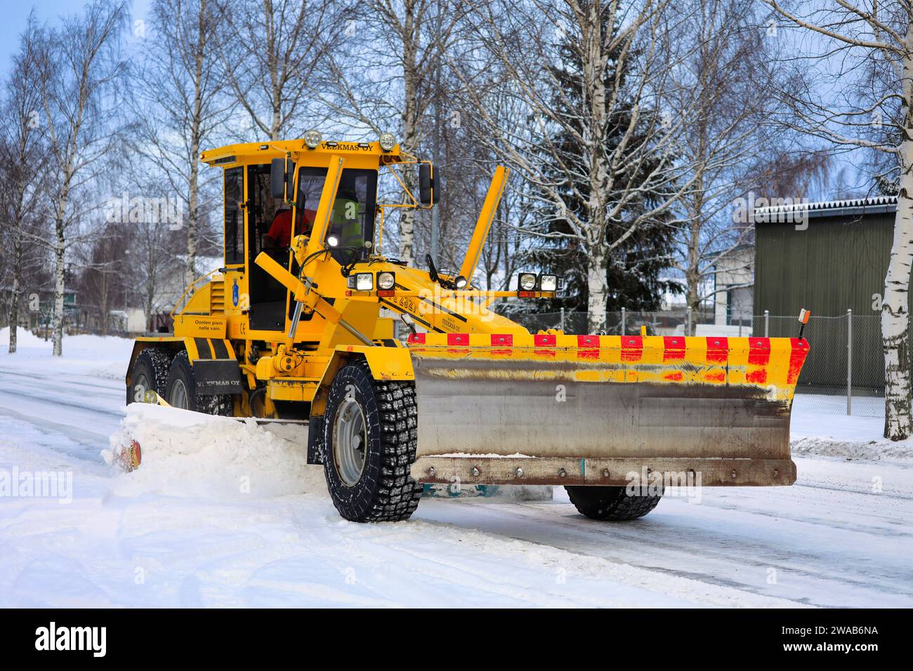 Yellow motor grader Veekmas FG 2327 S removing snow from street with ...