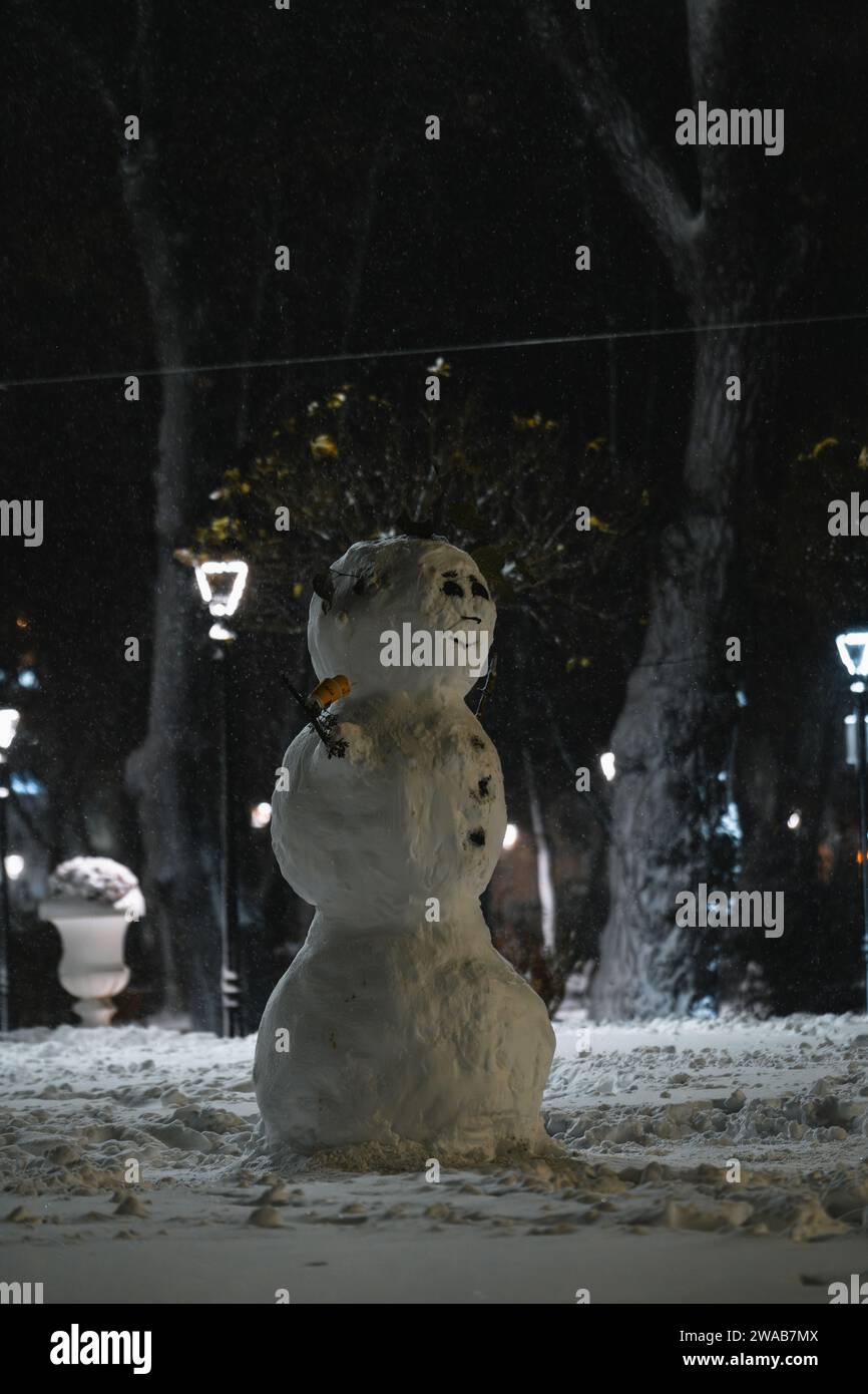 Snowman on snowy evening, park lights glimmer Stock Photo - Alamy