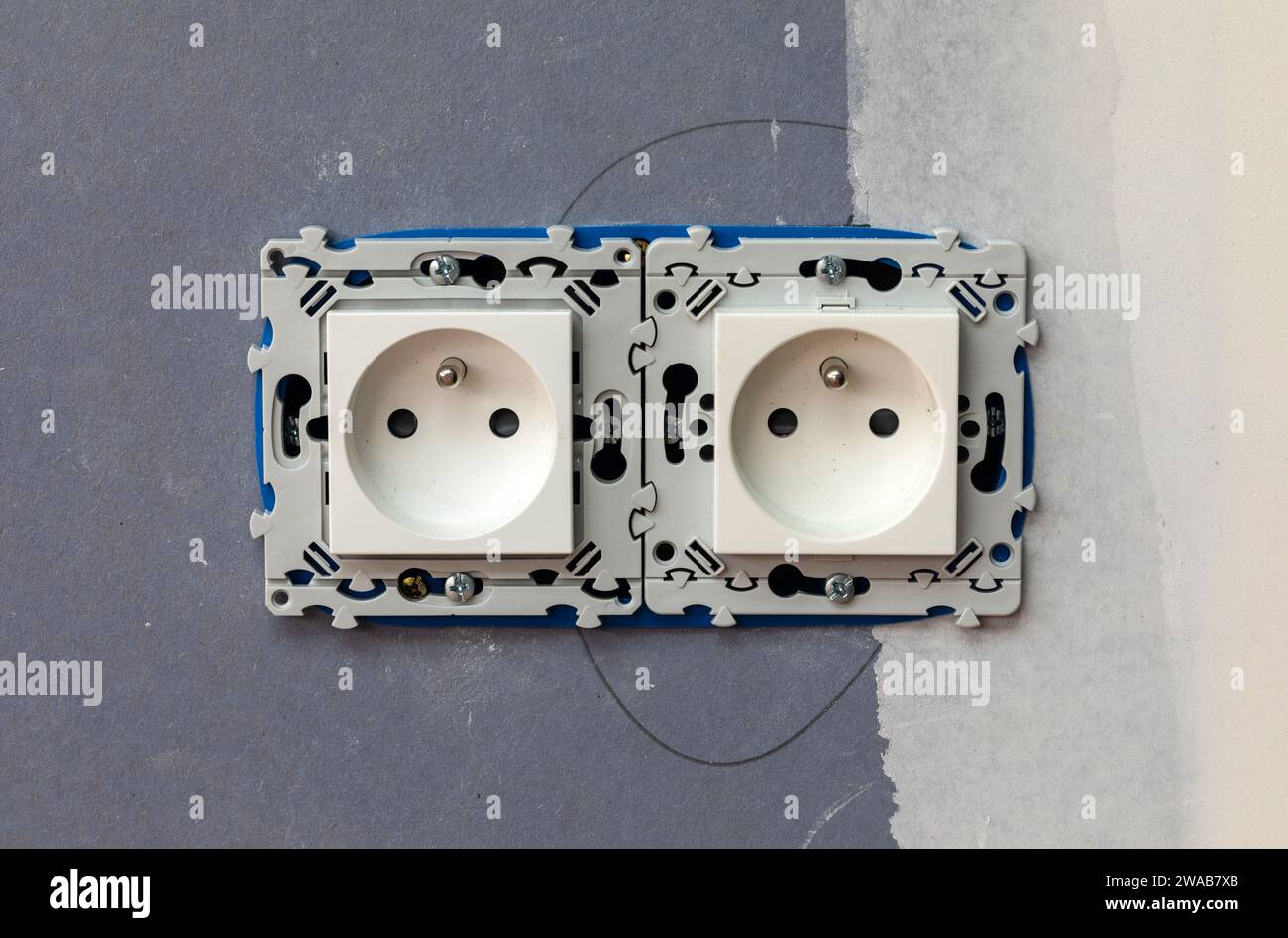 Two-slot electrical outlet socket installation on blue wallboard Stock ...