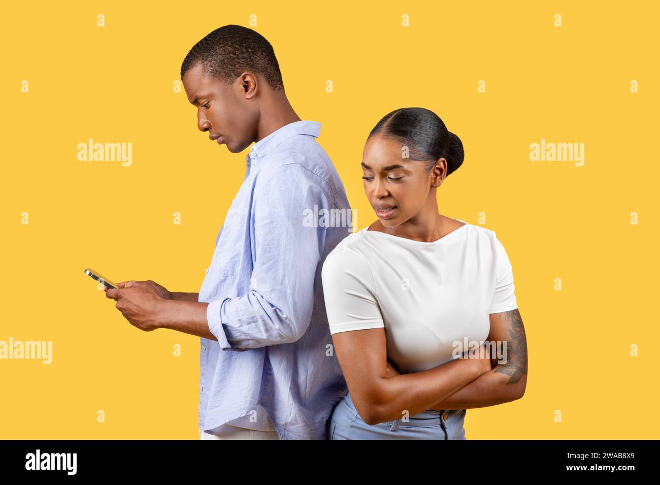 Black man on phone ignoring woman, both upset, yellow background Stock ...