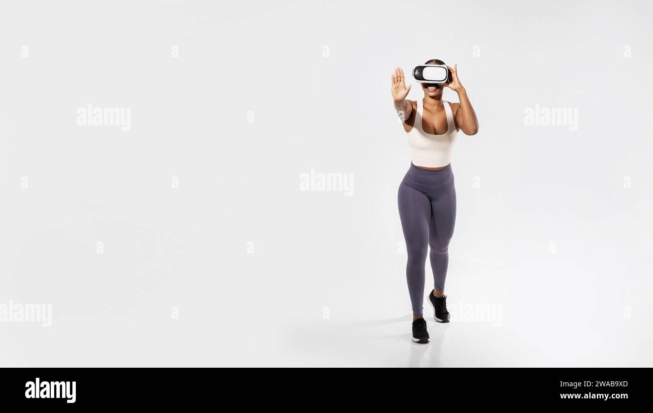 Sporty black lady experiencing virtual reality training on white ...