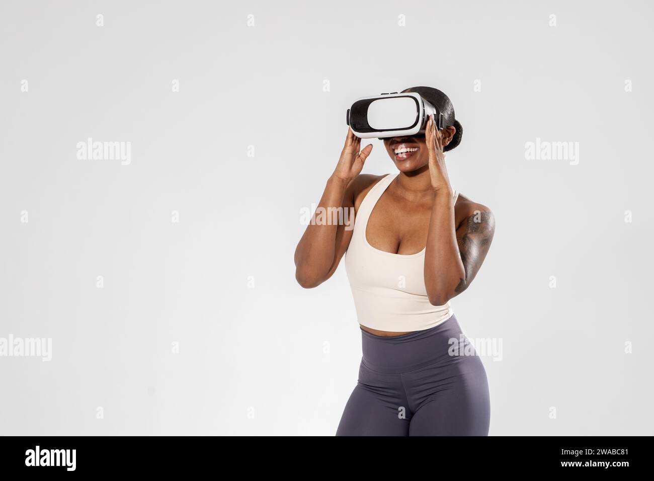 black woman in activewear immersed in VR exercise, white backdrop Stock ...