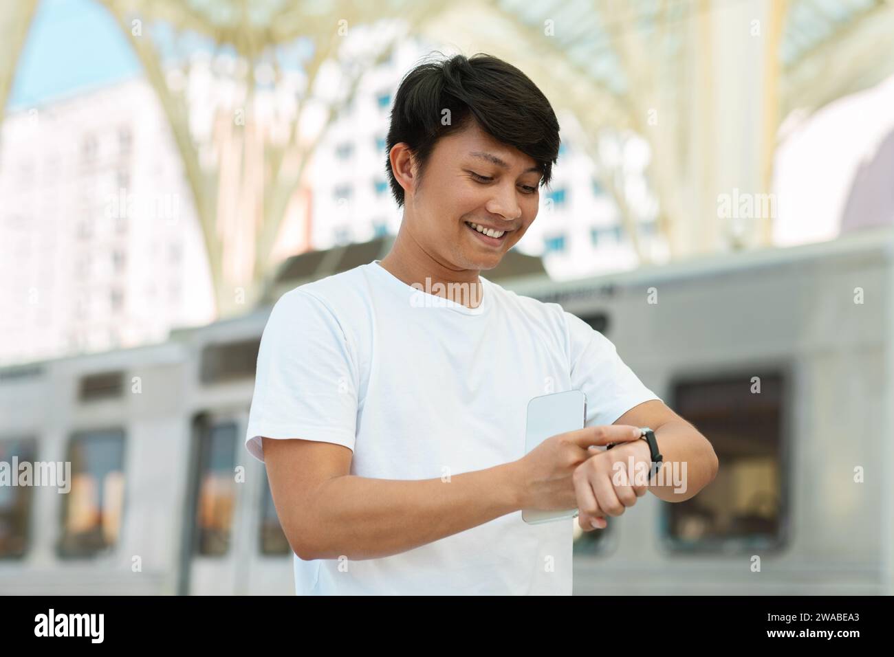 Smiling chinese man looking at watch standing on city street Stock ...
