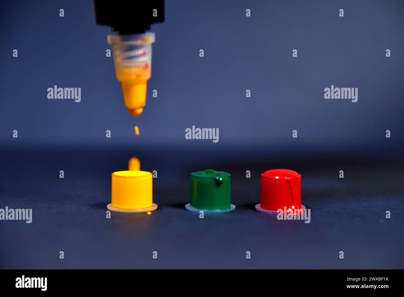 Yellow ink dripping in small plastic cup. Art And design concept. Close ...