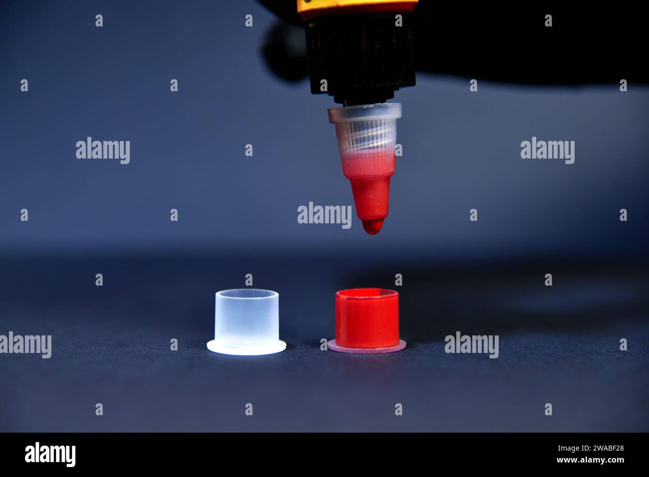 Red ink dripping in small plastic cup. Art And design concept. Close up ...