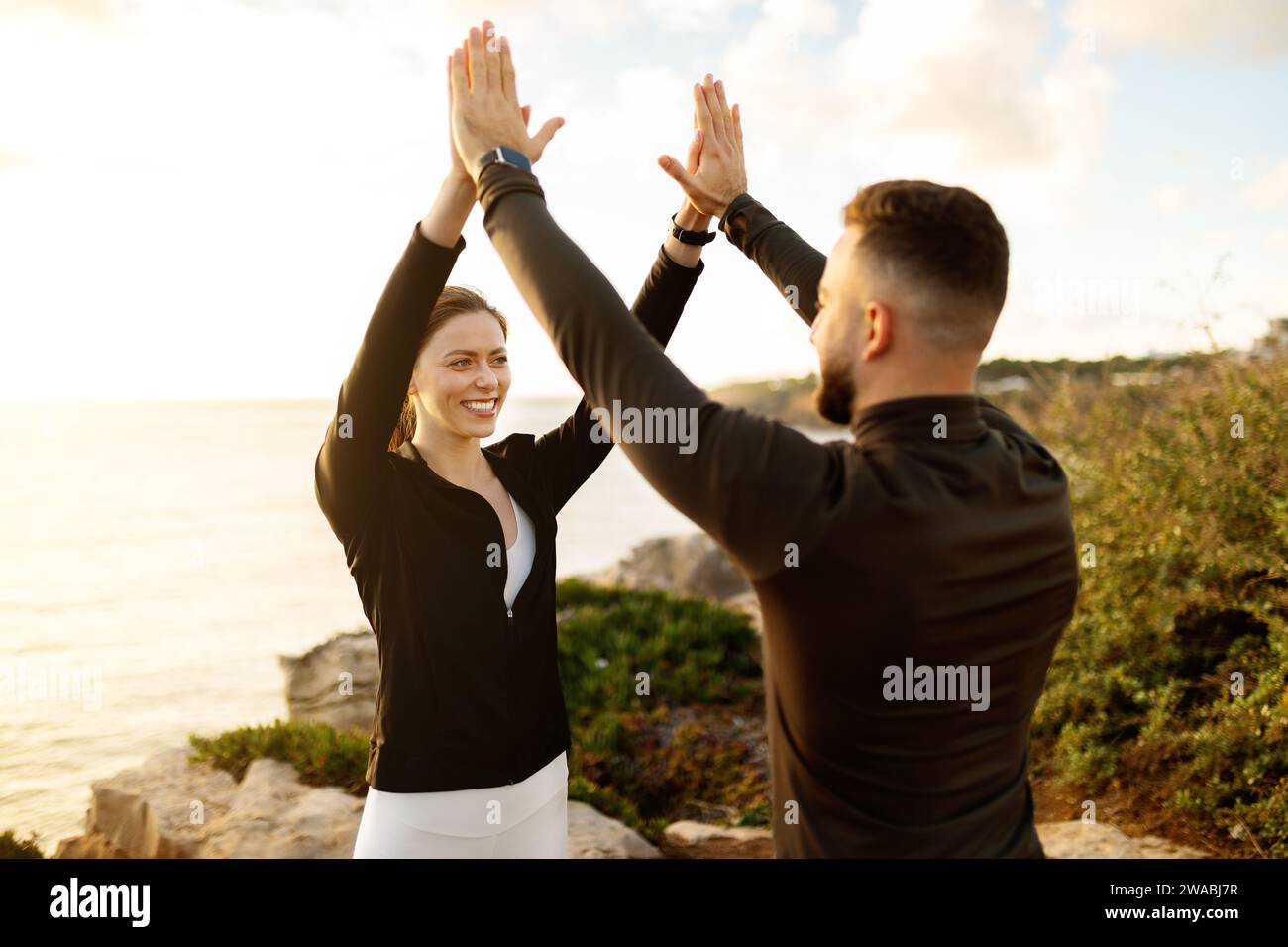 Joyful couple high-fiving during outdoor workout at sunrise Stock Photo ...