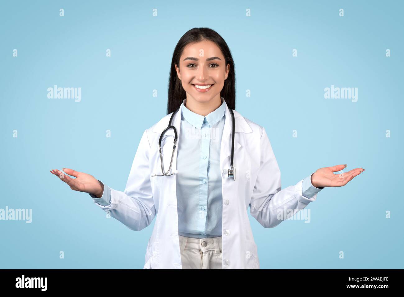 Balanced female doctor with open palms, blue backdrop Stock Photo - Alamy