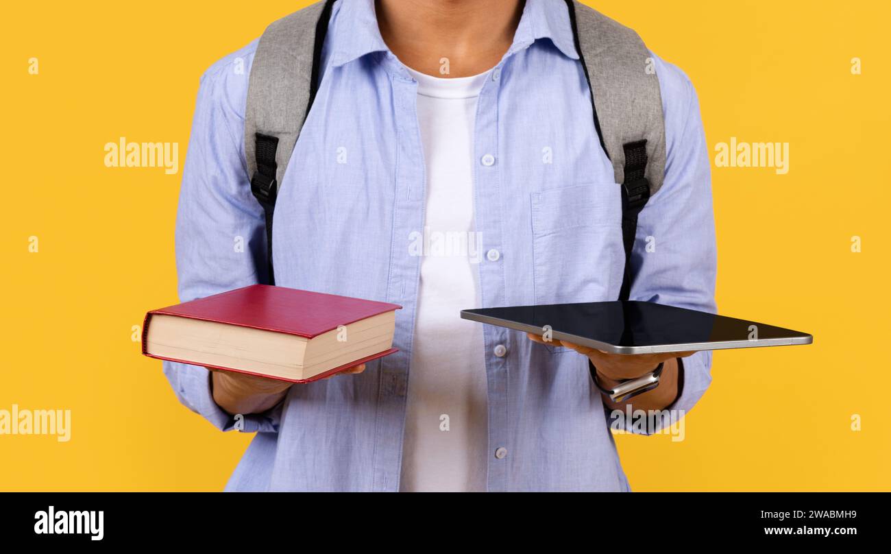 Student male comparing book with tablet on yellow background Stock ...