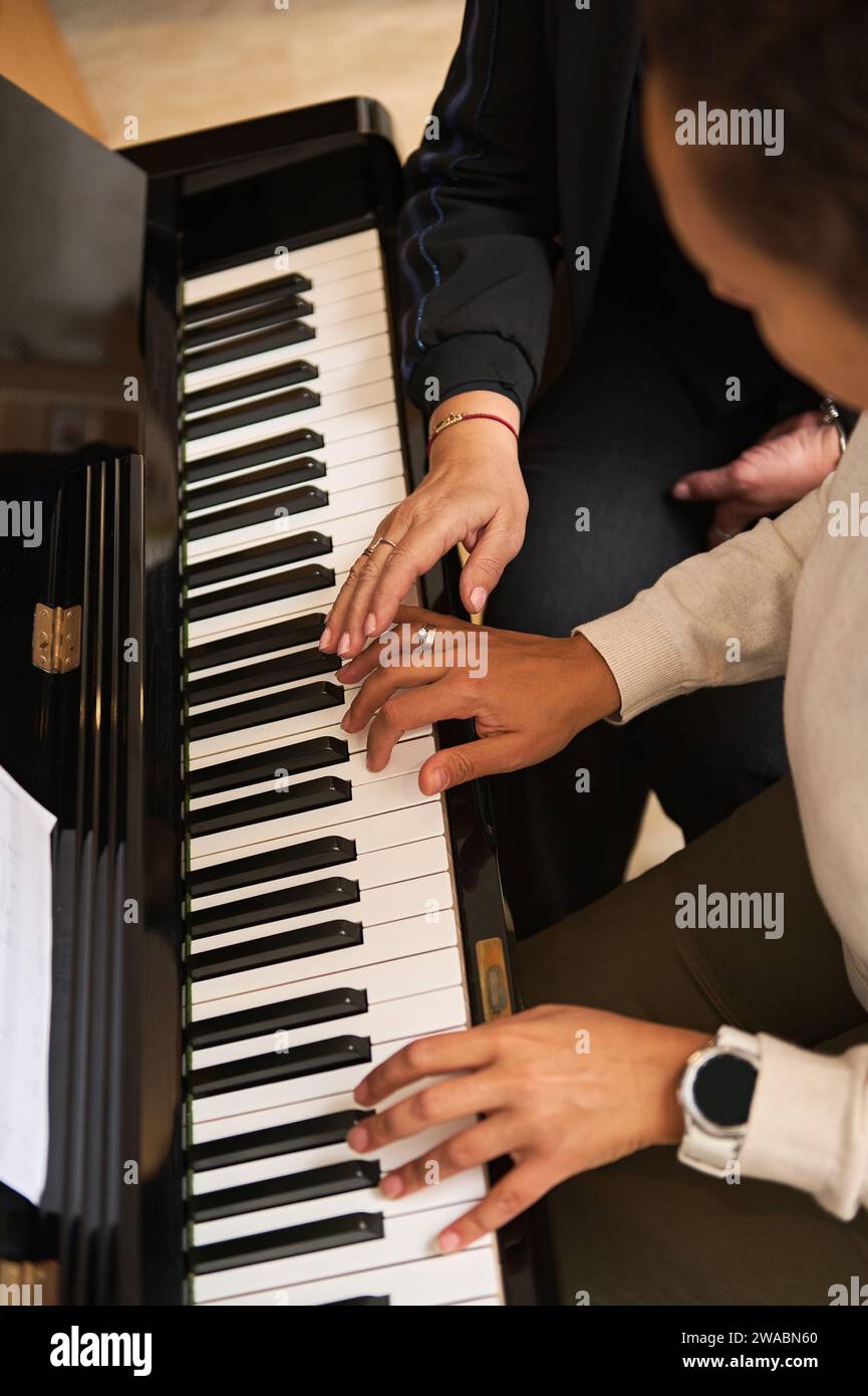 Overhead view of a young woman learning playing piano, touching piano ...