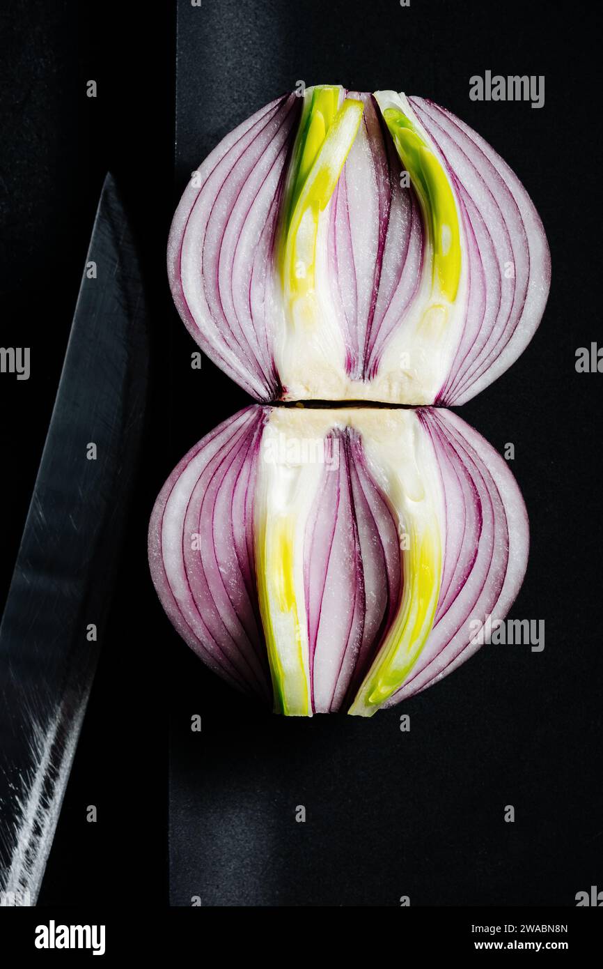 Red onion cut in half on a black background Stock Photo - Alamy