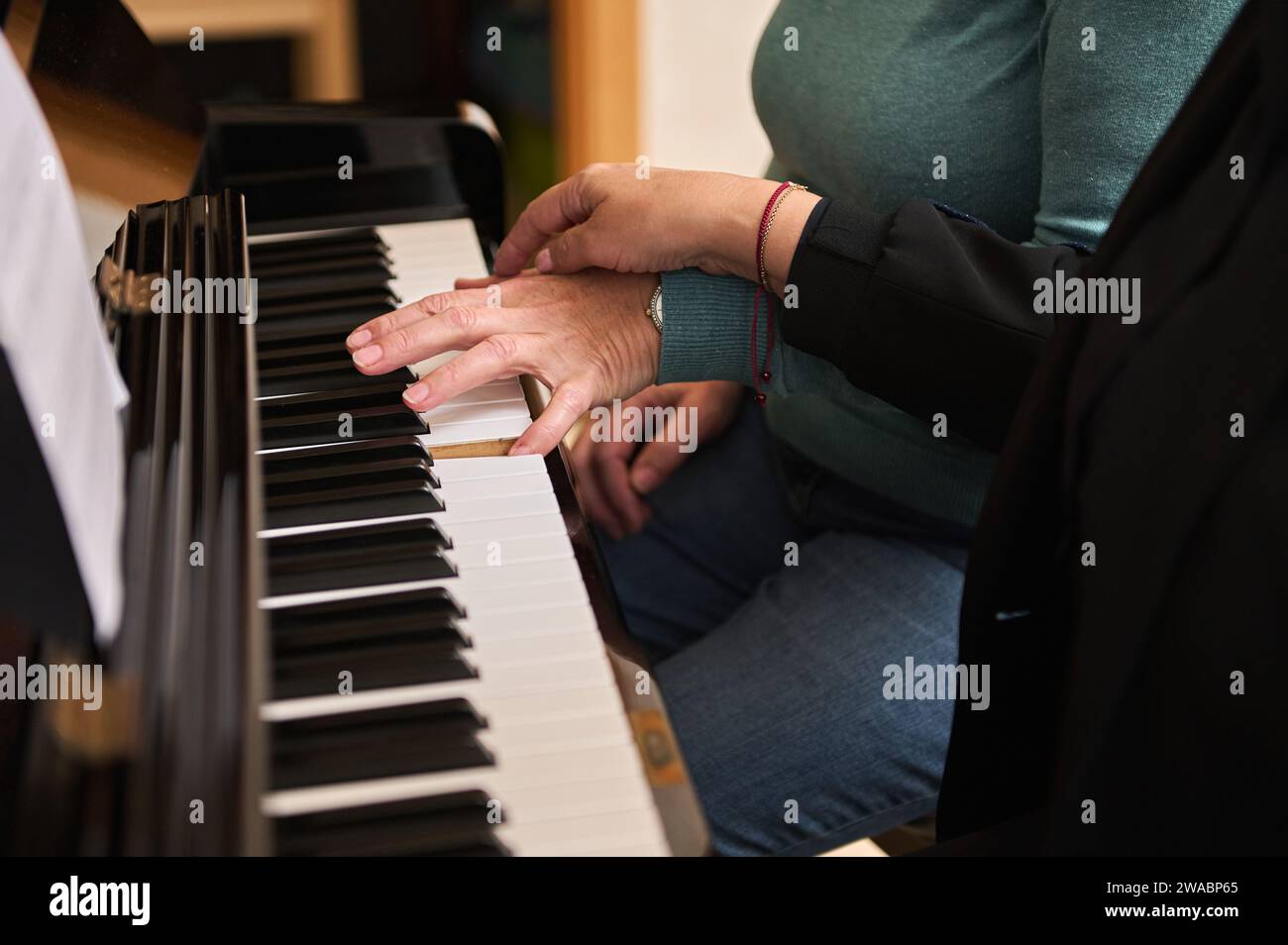 Close-up two women musicians pianists playing together the piano in ...