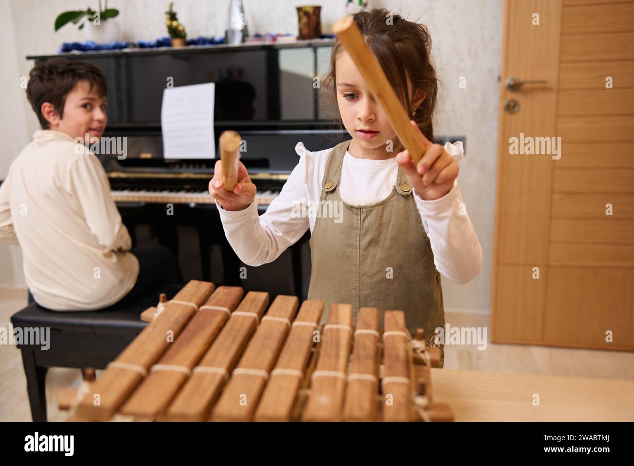 Adorable teenage boy and little girl enjoy playing together on musical ...