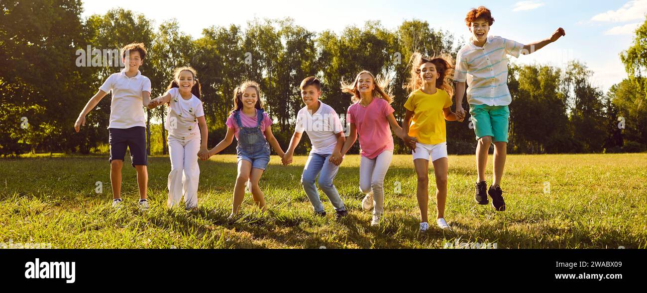 Happy teenage kids friends having fun and jumping in the park standing ...