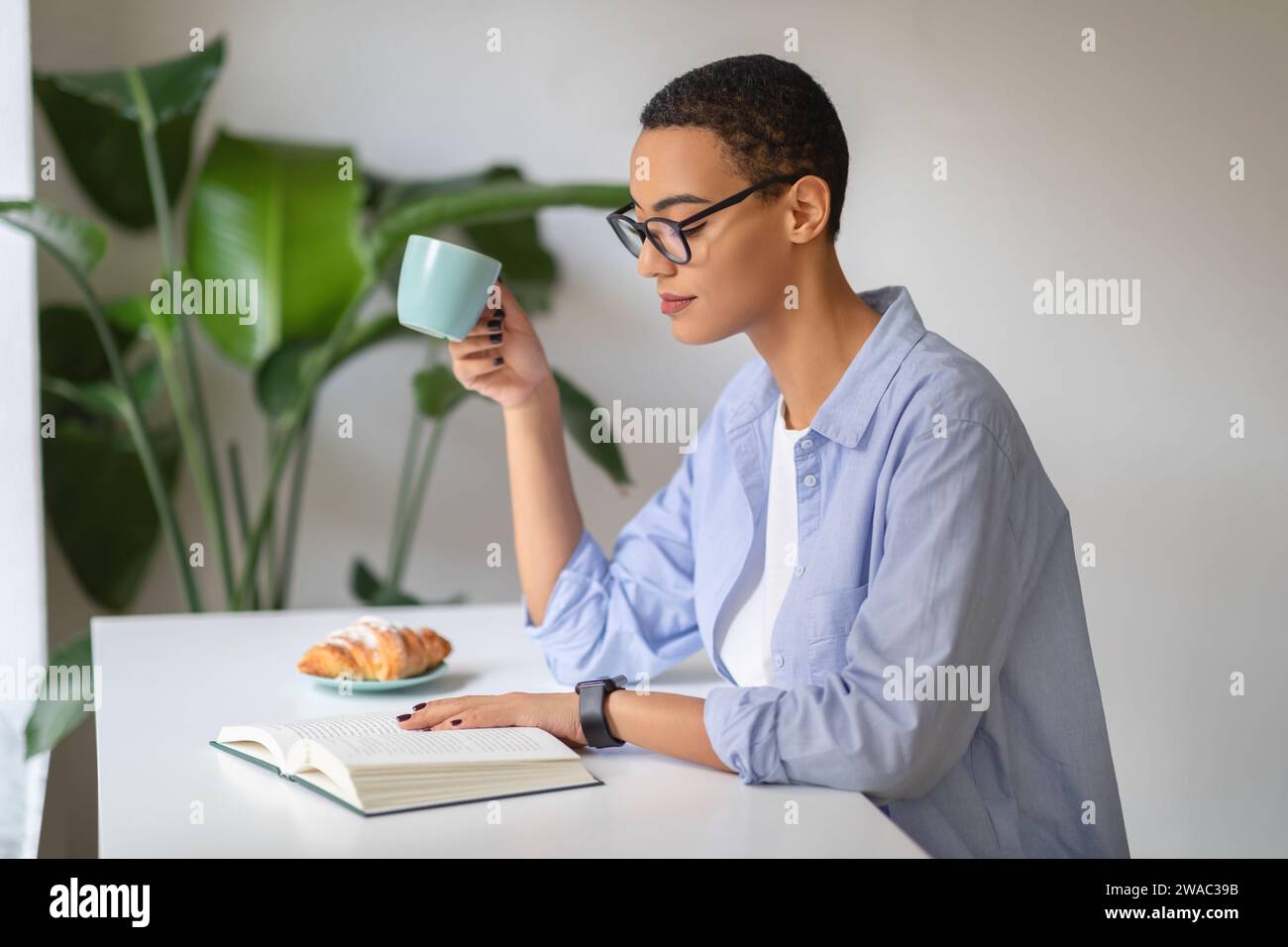 A contemplative young woman enjoys her morning coffee while reading ...