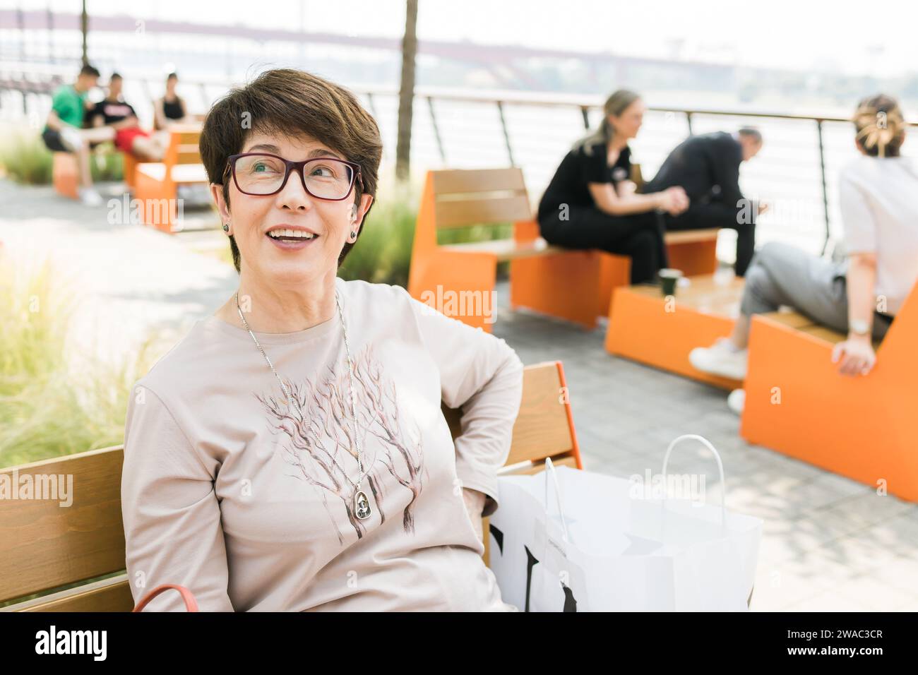 Outdoor portrait of beautiful and elegant middle age 55 - 60 year old woman wearing long sleeve ...