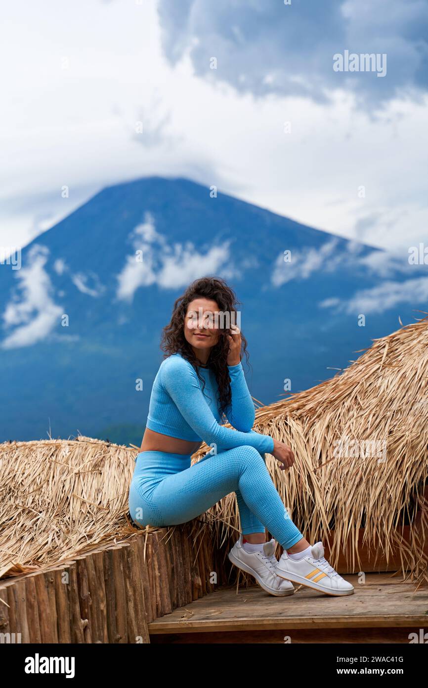 A young woman poses on a large straw photo zone as a bird on a viewing ...