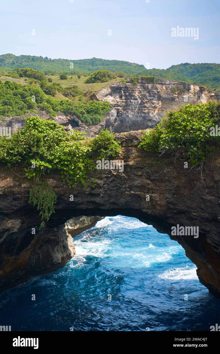 Rock broken by an ocean wave forming an arch in the mountain. Cliff is ...