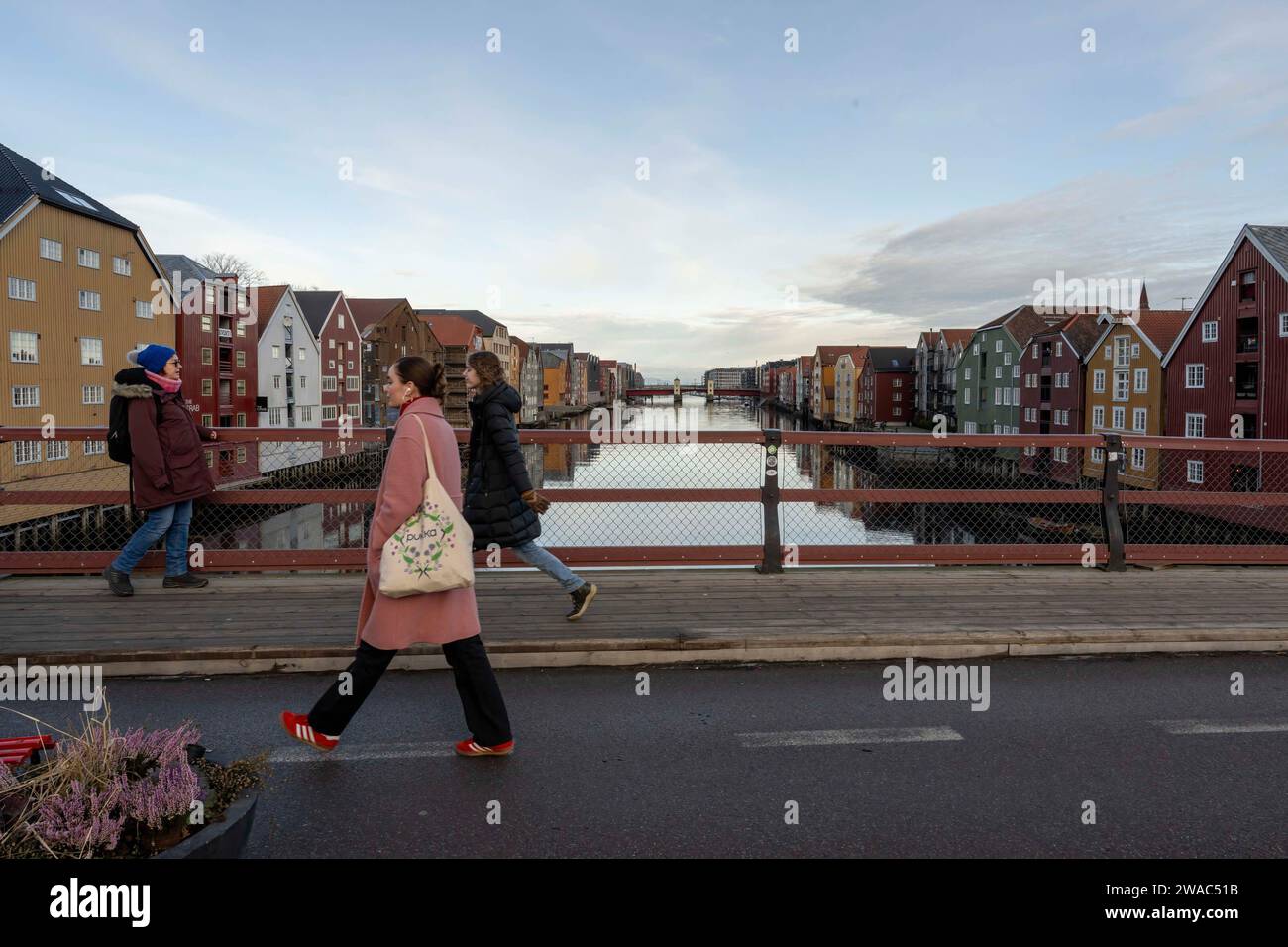 Several people walk along a footbridge across the Nidelva river in the ...