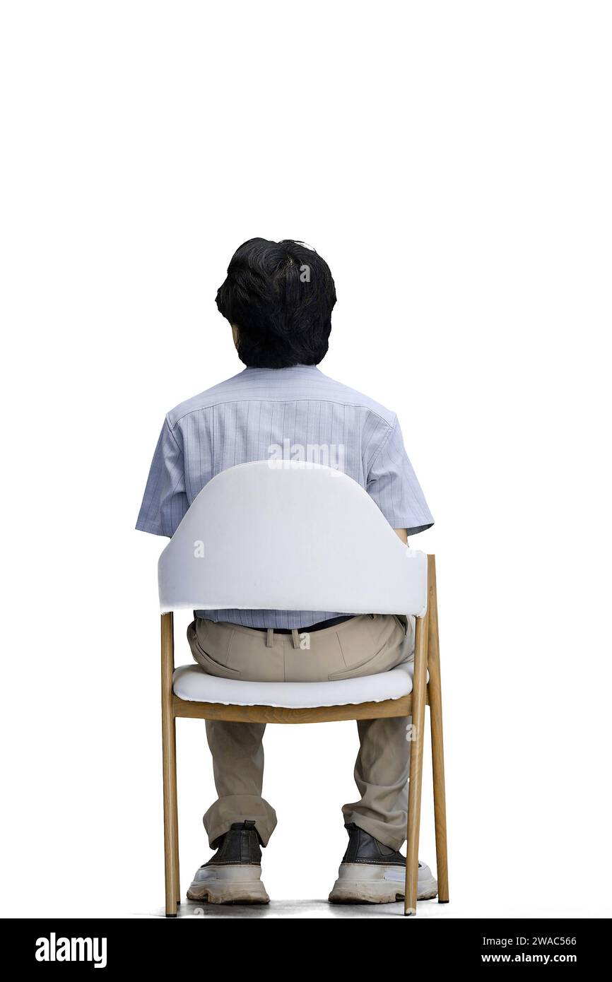 A guy in a blue shirt, on a white background, is sitting on a chair ...