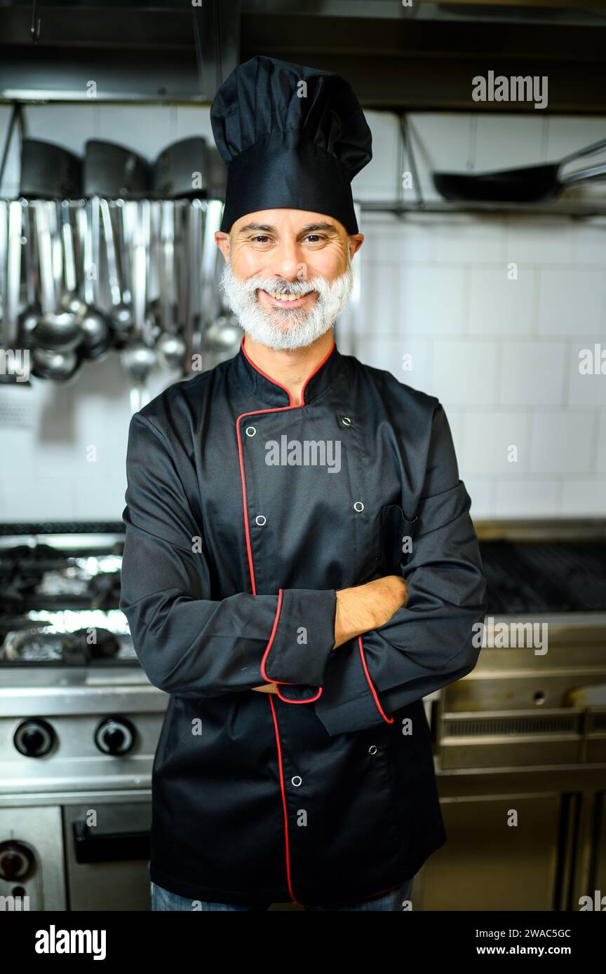 Confident male chef in uniform poses proudly in a commercial kitchen ...