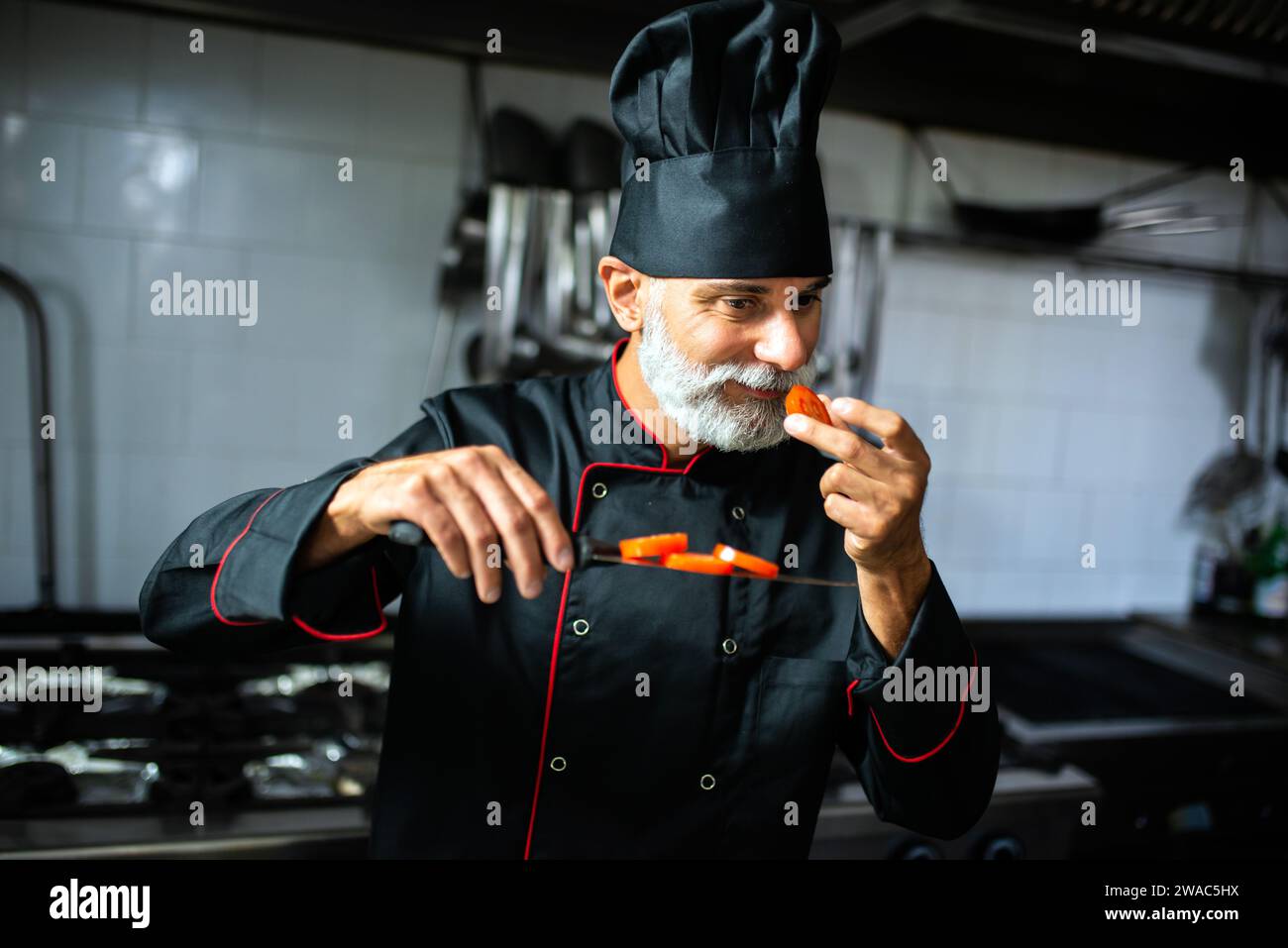Professional chef sampling a dish with a focused expression in a ...
