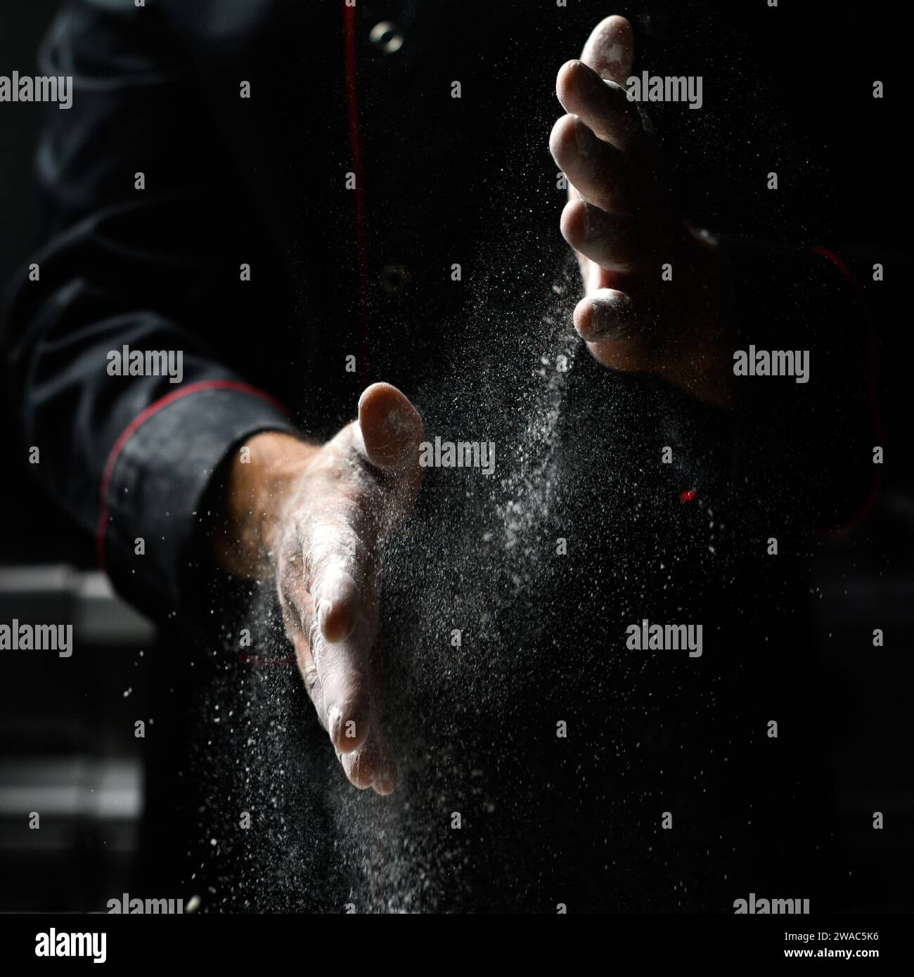 Closeup of chef's hands sprinkling flour, dark background Stock Photo ...