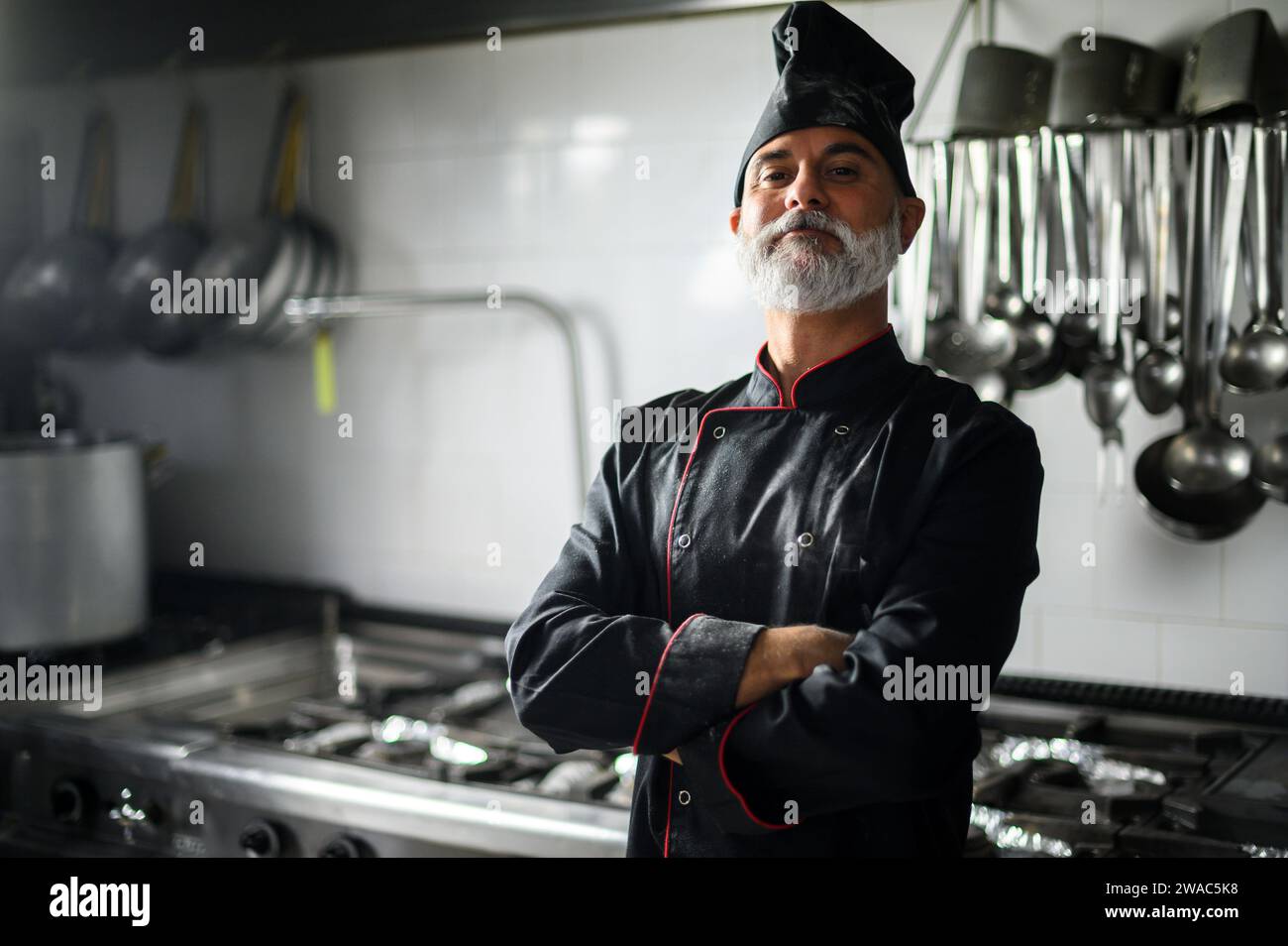 Mature chef in black coat with folded arms in his kitchen Stock Photo ...