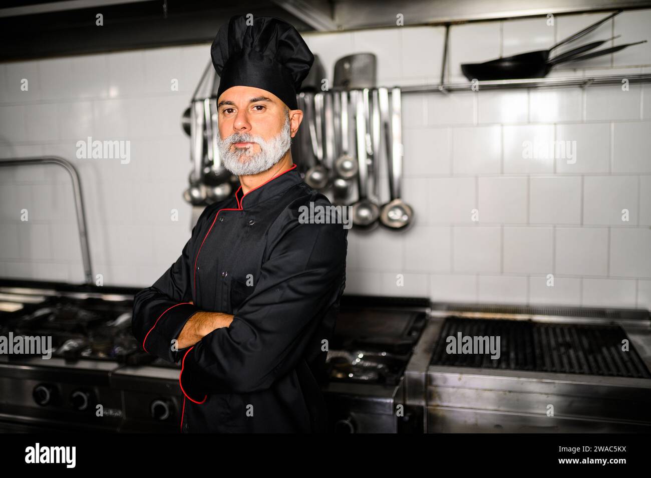 Mature chef in black coat with folded arms in his kitchen Stock Photo ...
