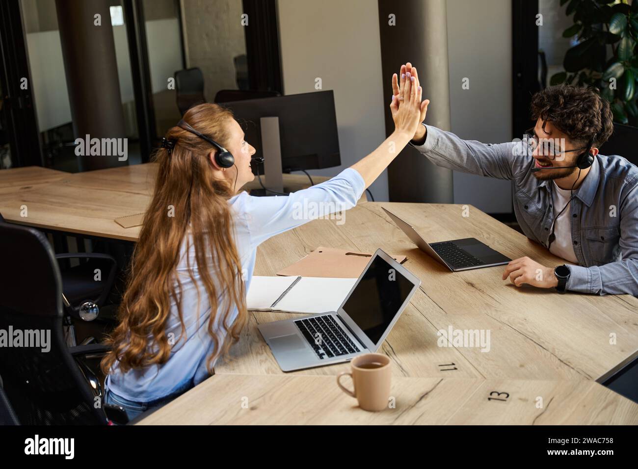 Young smiling european call center operators giving high five each ...