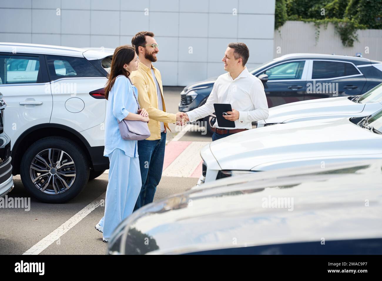 Car dealership employee communicates with couple of clients before test ...