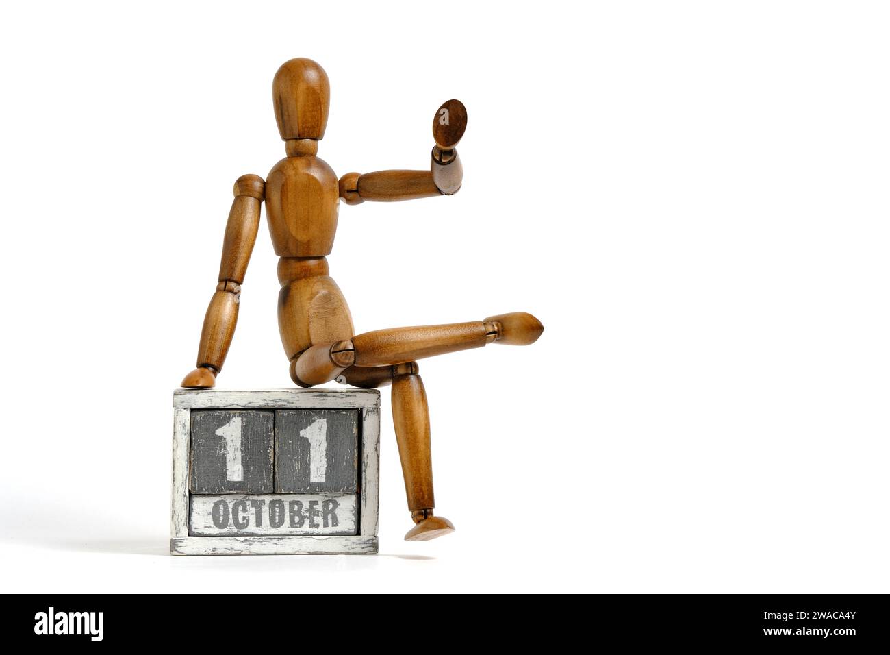 October 11, wooden calendar with mannequin sitting on it on white ...