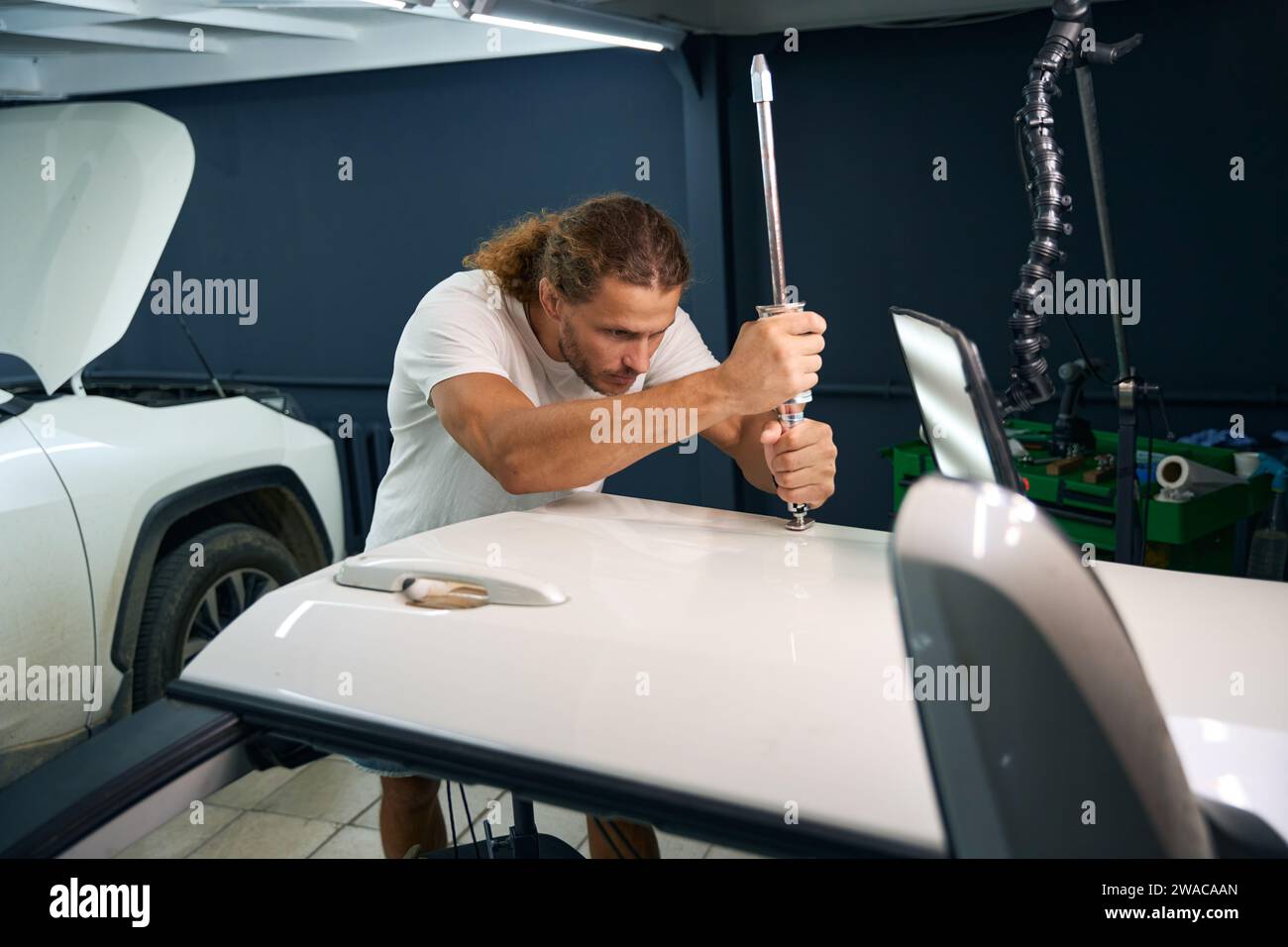 Man uses a special tool to level out body dents Stock Photo - Alamy