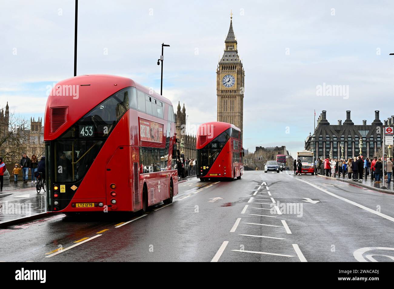 London Buses cross Tower Bridge on a wet day with Big Ben in the ...