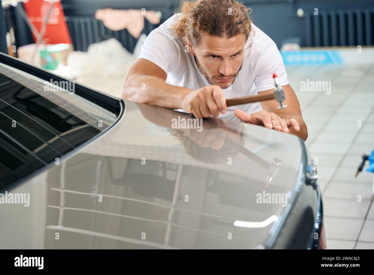 Experienced master straightens body of white car with straightening ...