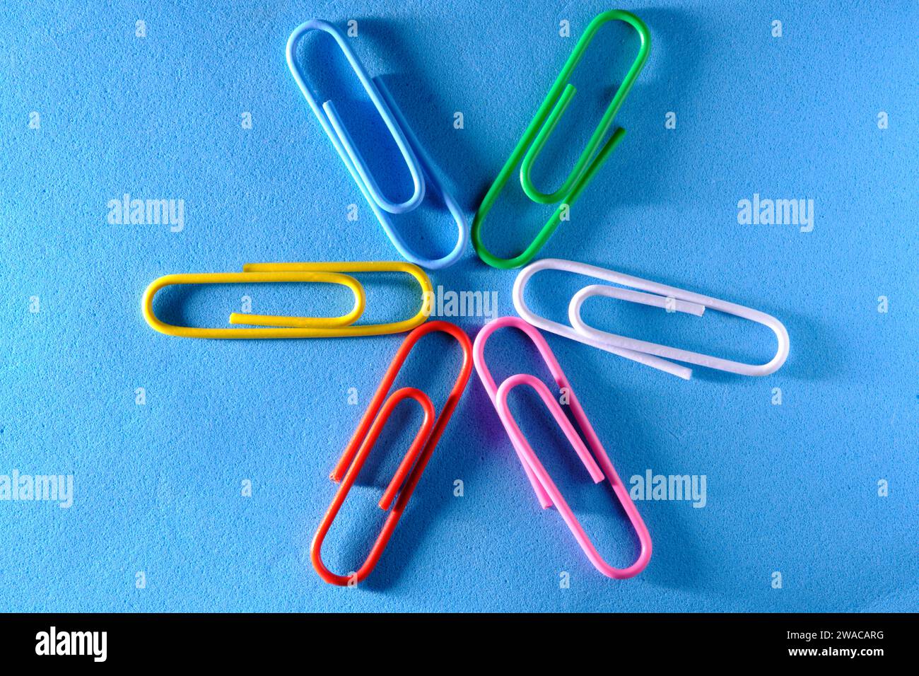 Multi colored paper clips are folded in shape star blue background ...