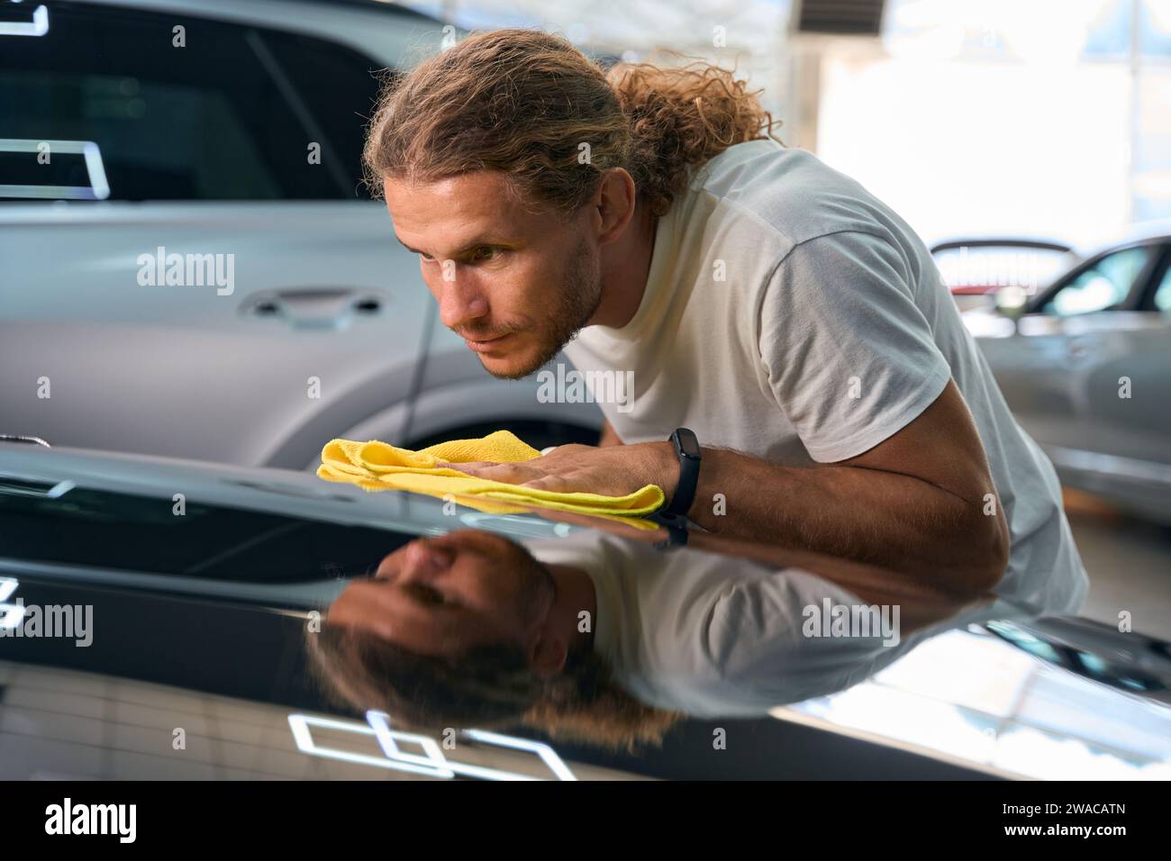 Long-haired man uses a soft cloth to polish the hood Stock Photo - Alamy
