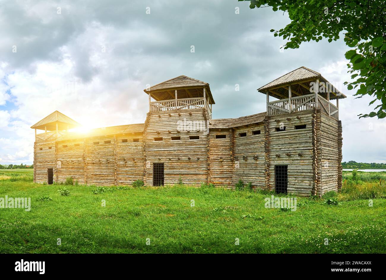 An old wooden fortress surrounded by a fence with sharp peaks on a ...