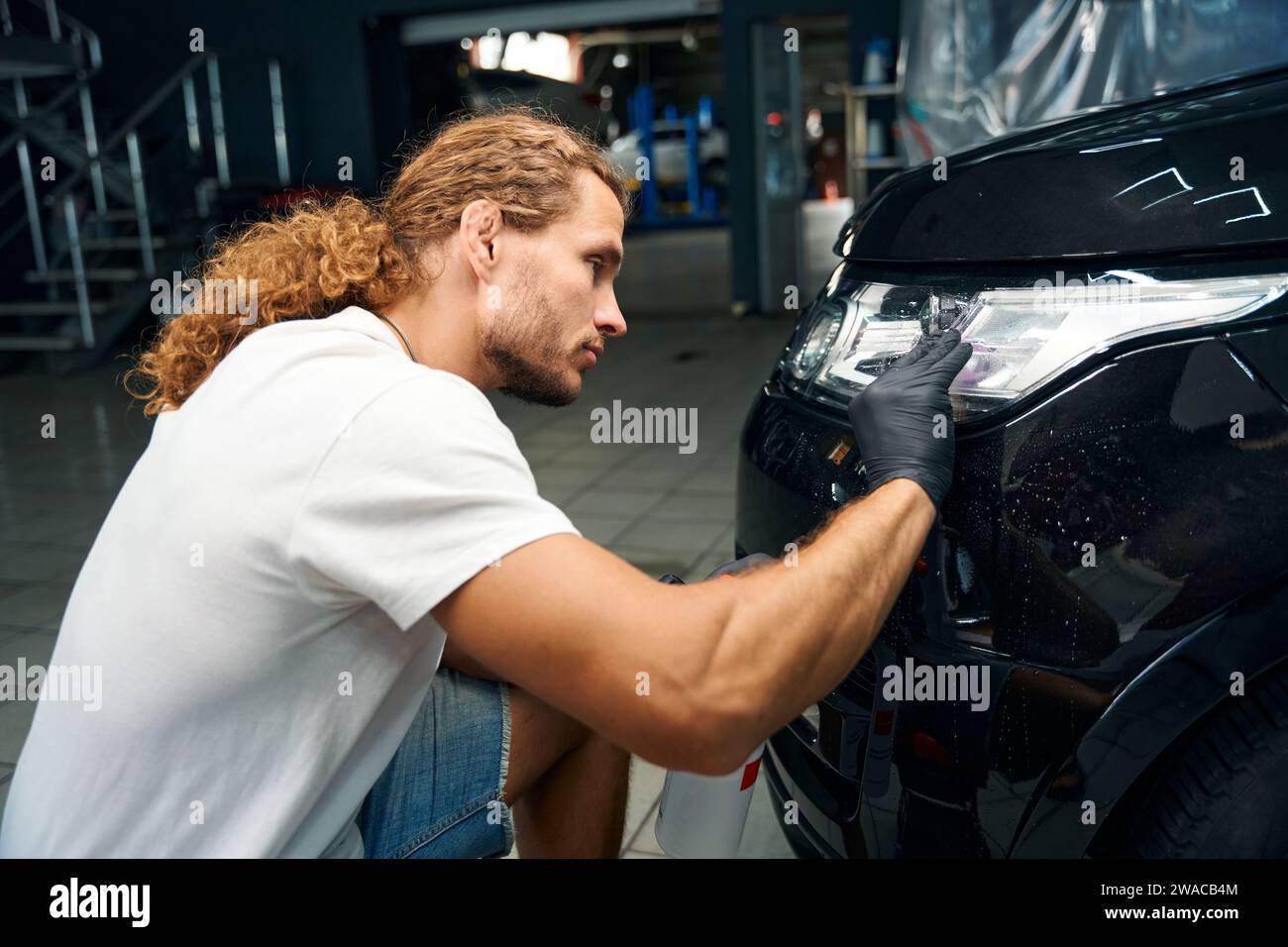 Guy works in a car repair shop detailing black car Stock Photo - Alamy
